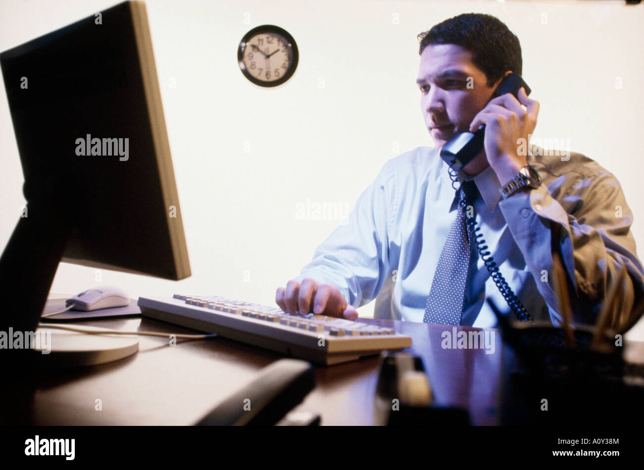 Close-up of a businessman using a computer and a telephone in an office ...