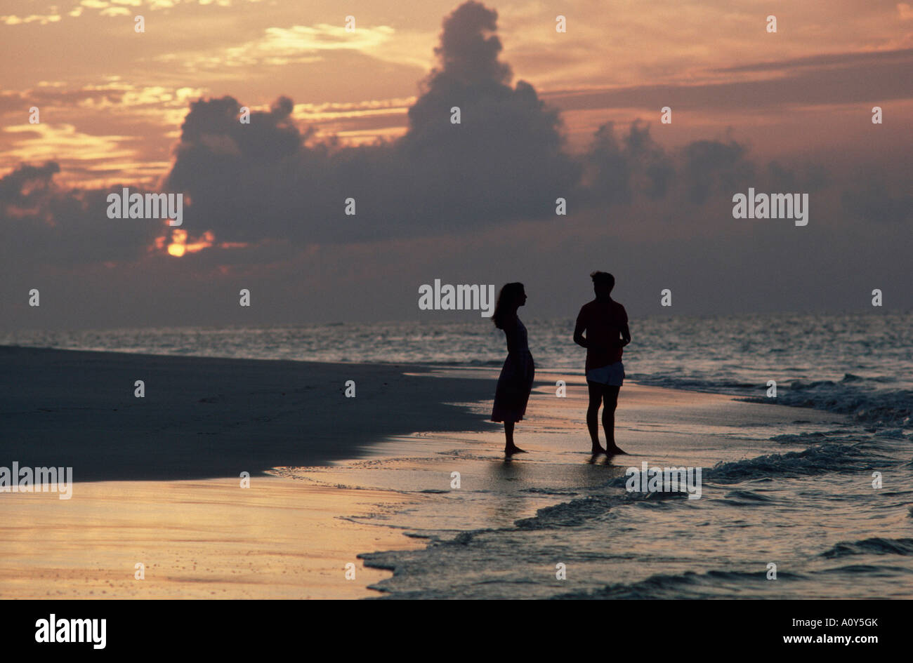Silhouette of a young couple standing on the beach Stock Photo - Alamy