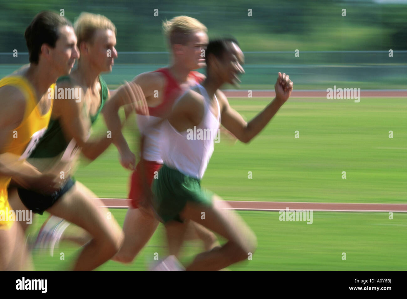 Side profile of four athletes running on a running track in a race ...