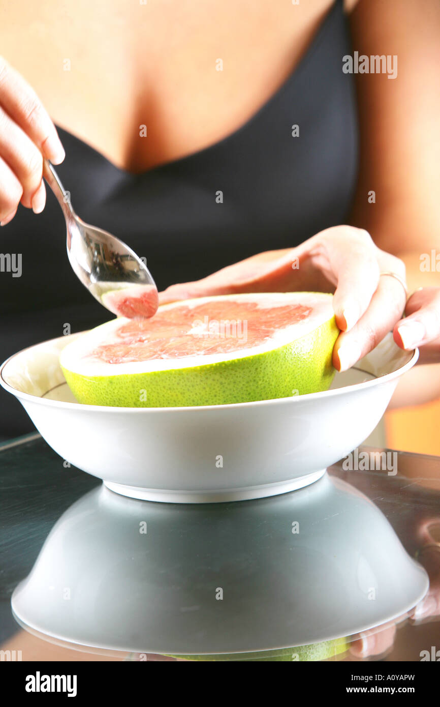 Young Woman Eating Half A Healthy Ripe Pink Breakfast Grapefruit From A ...