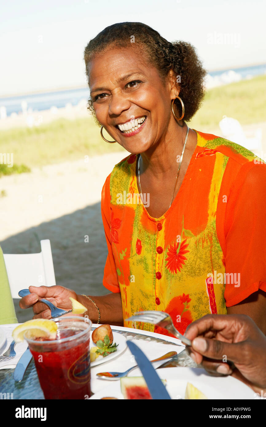 Middle-aged African woman eating at the table outdoors Stock Photo - Alamy