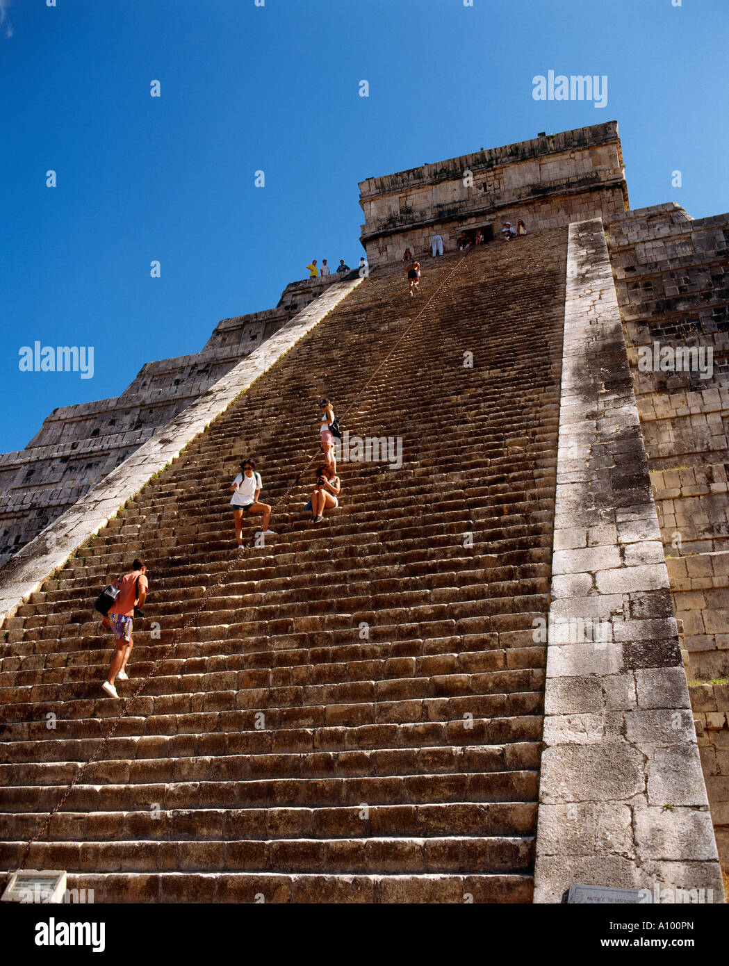 People walking up the steep steps on the Pyramid of Kukulcan which ...
