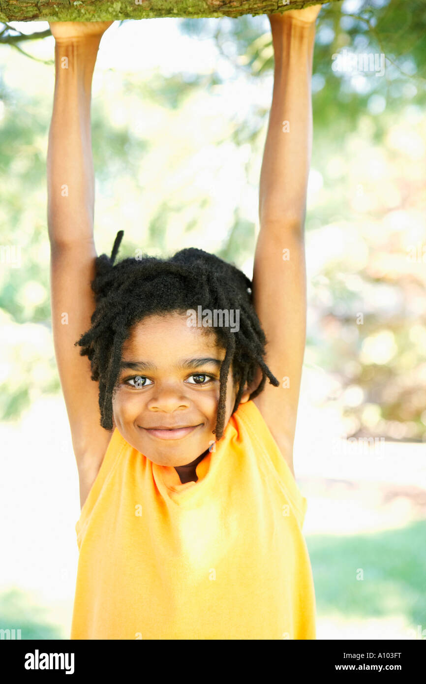 Young African boy hanging from tree branch Stock Photo - Alamy