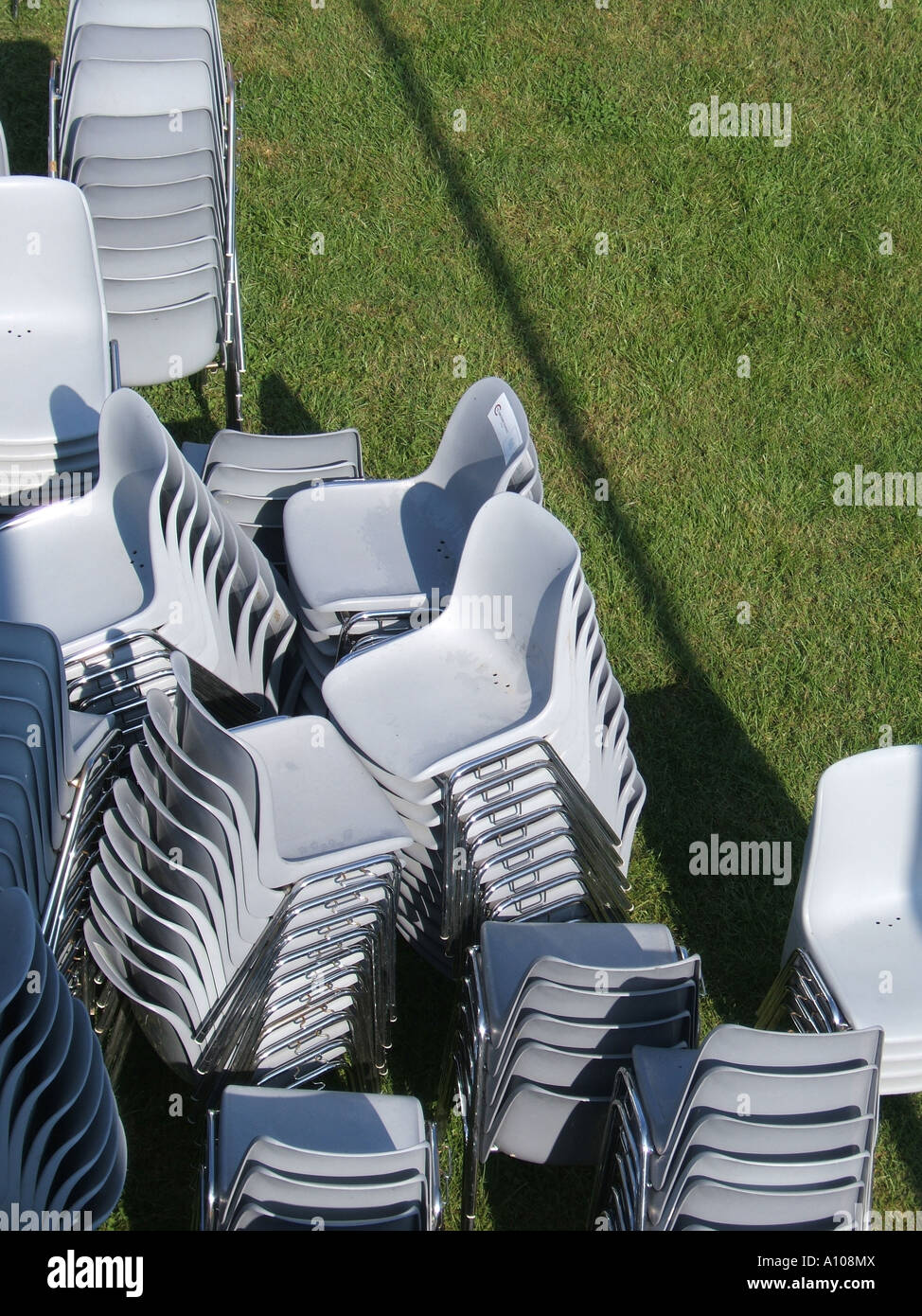 stacks of white plastic chairs in field Stock Photo - Alamy
