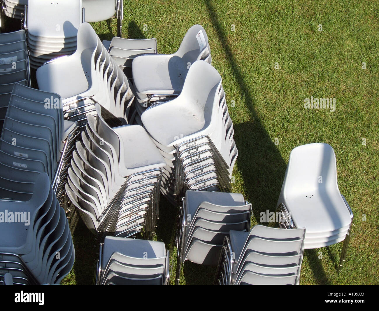 stacks of white plastic chairs in field Stock Photo - Alamy