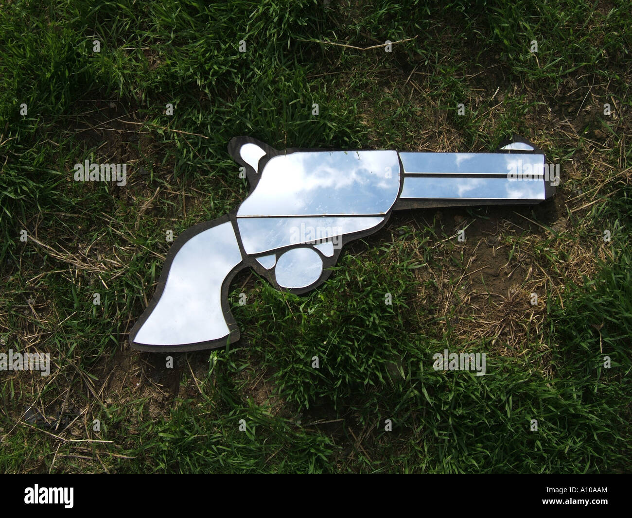 gun shaped mirror left outdoors with reflection of blue sky and clouds ...