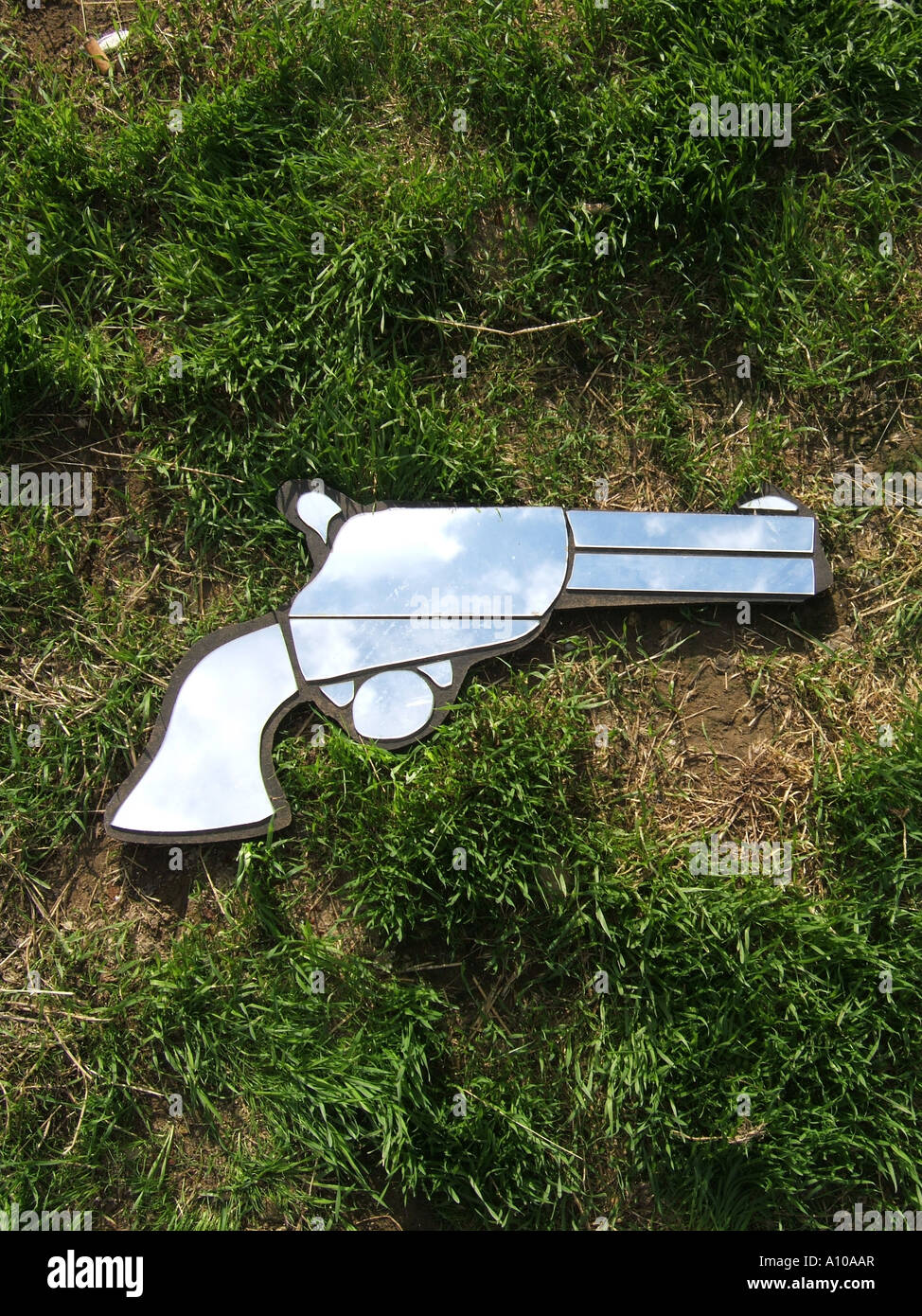 gun shaped mirror left outdoors with reflection of blue sky and clouds ...