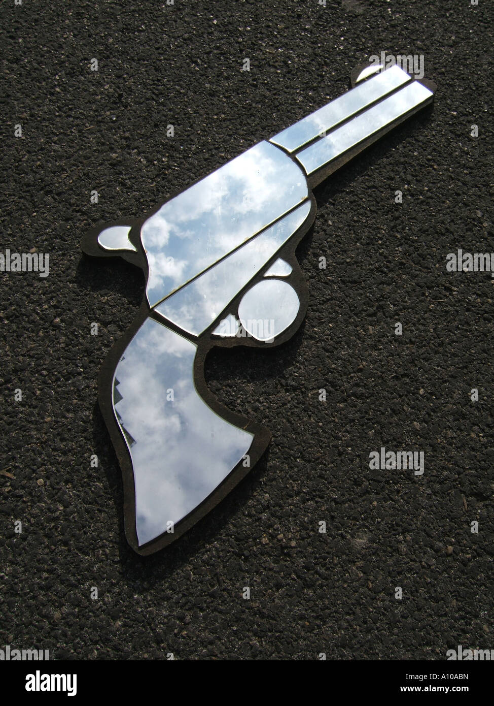gun shaped mirror left outdoors with reflection of blue sky and clouds ...