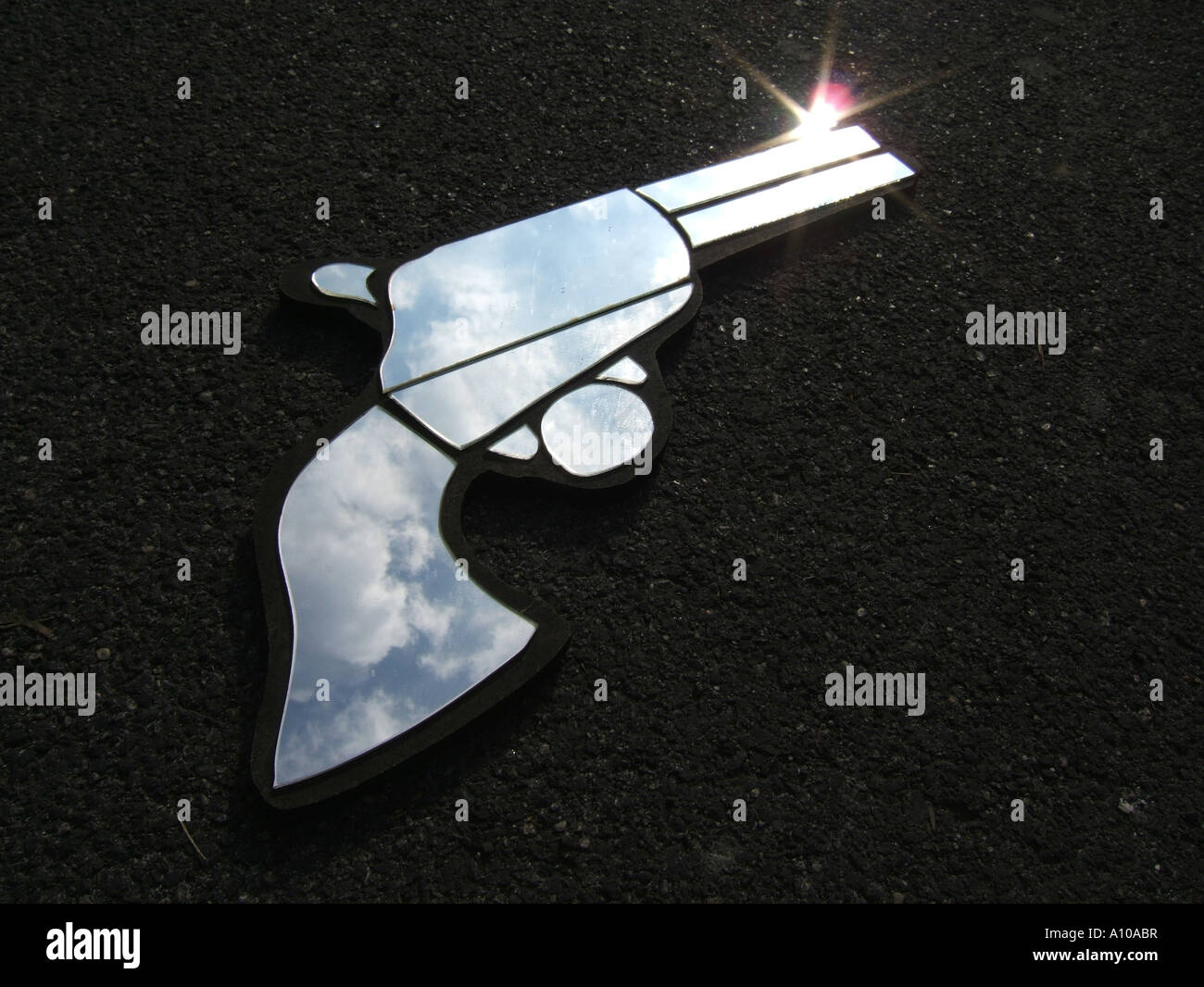 gun shaped mirror left outdoors with reflection of blue sky and clouds ...