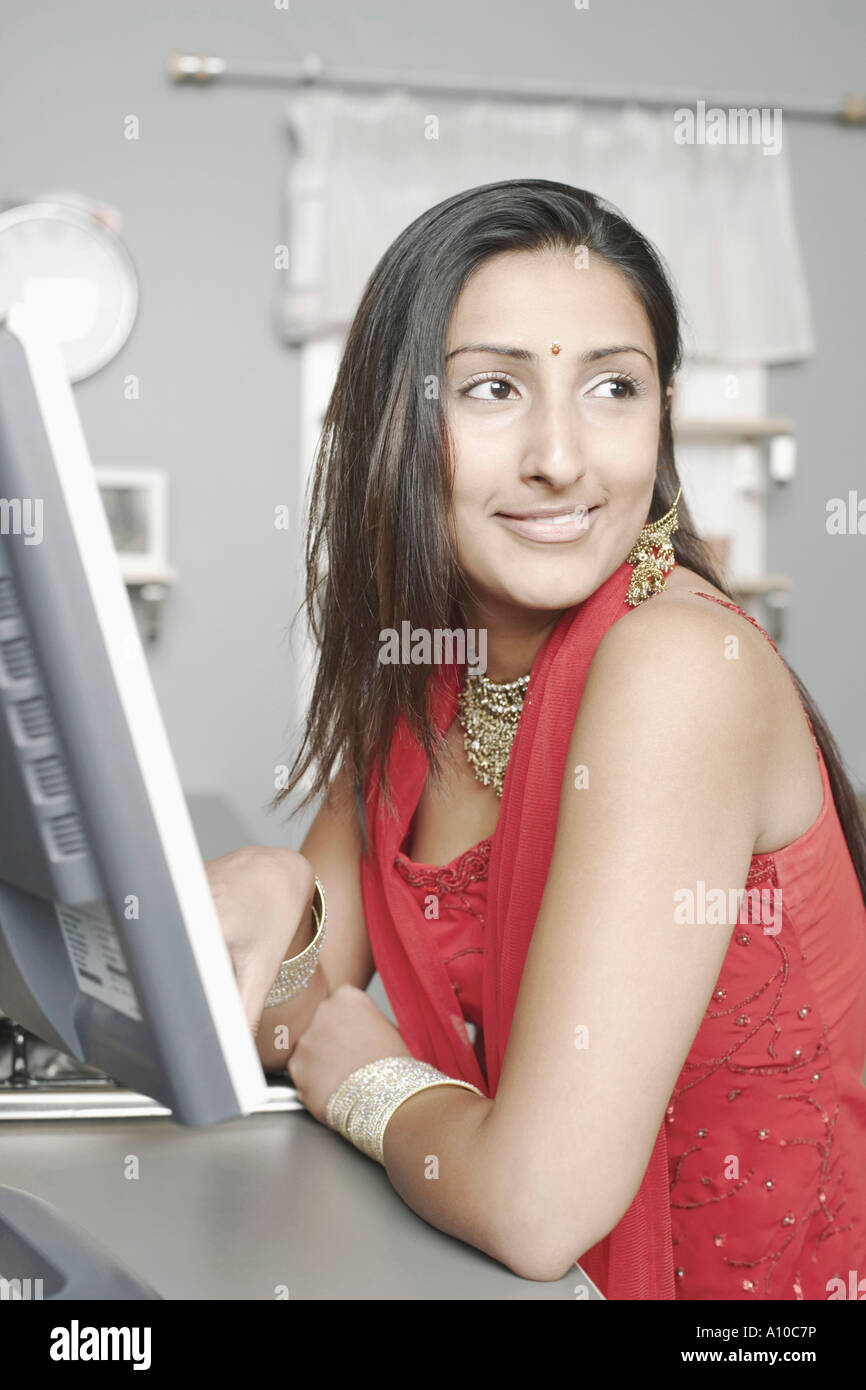 Side profile of a young woman sitting in front of a computer monitor ...