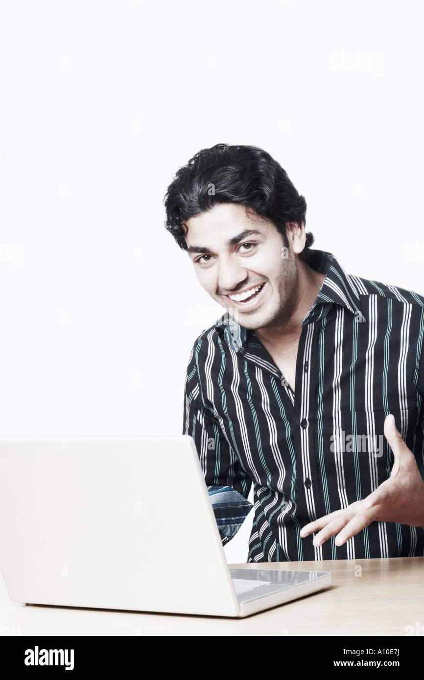 Portrait of a young man sitting in front of a laptop and smiling Stock ...