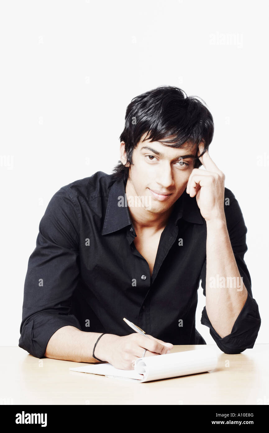 Portrait of a young man writing in a notepad Stock Photo - Alamy