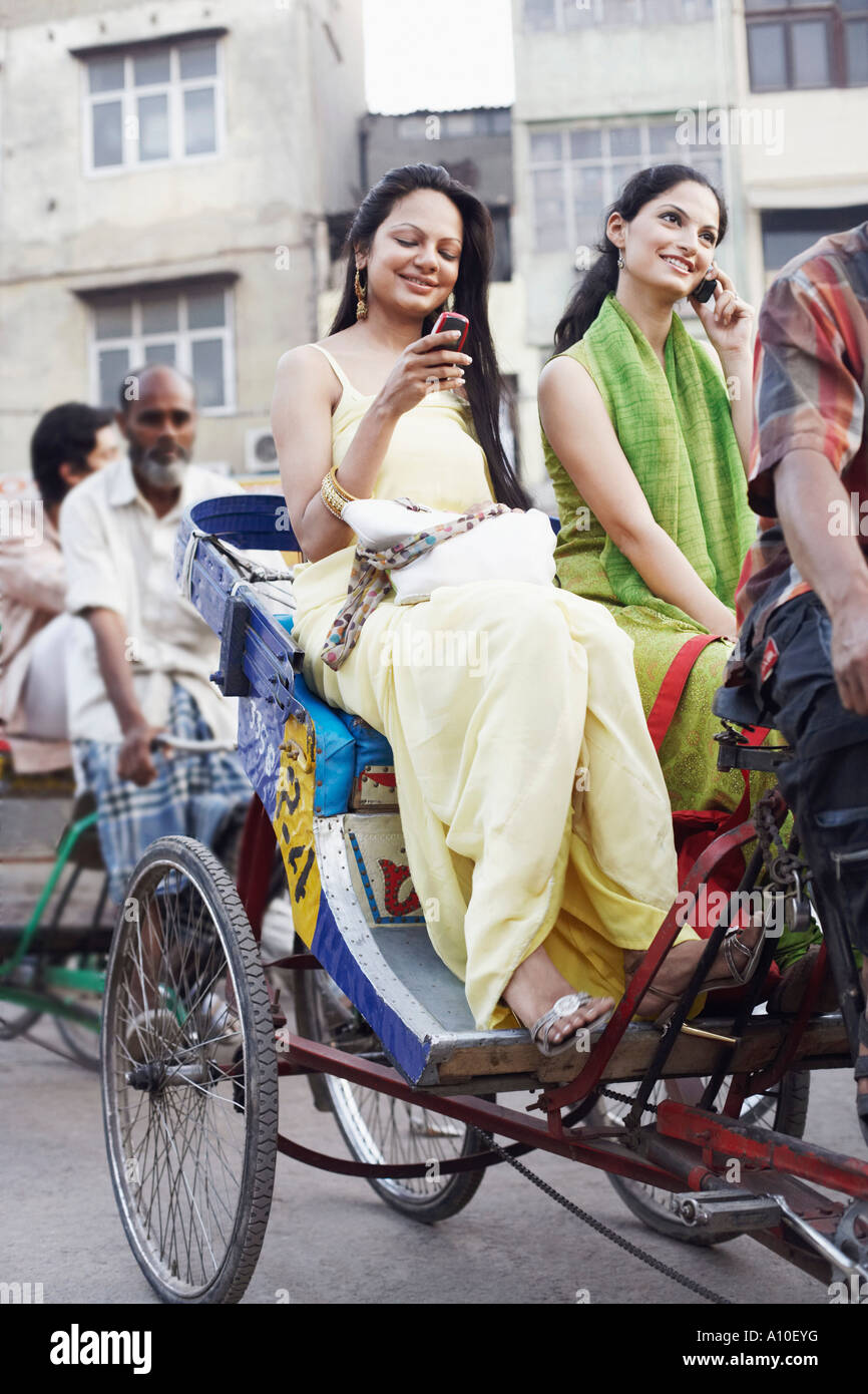 Two young women sitting in a rickshaw and using mobile phones Stock ...