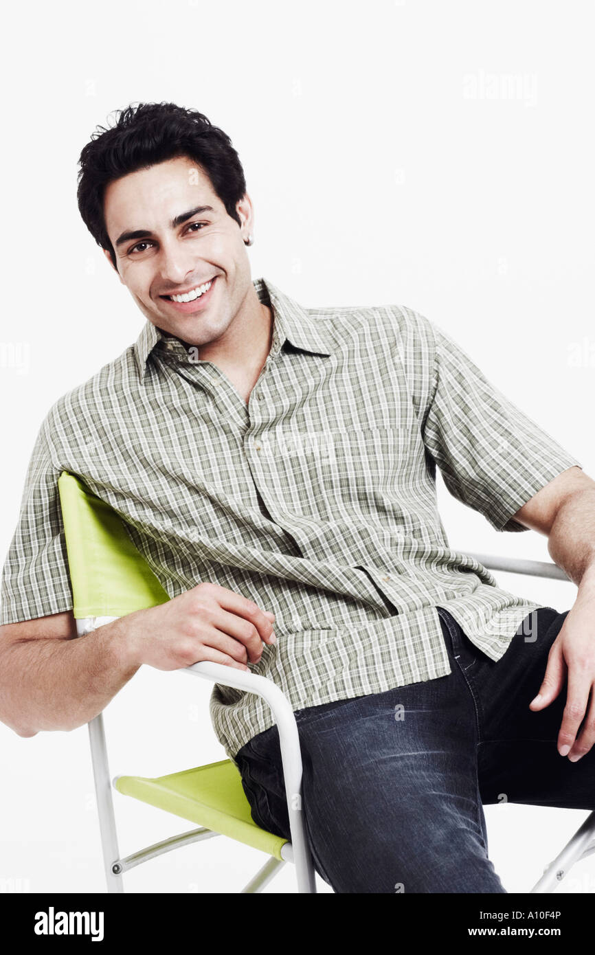 Portrait of a young man sitting on a folding chair and smiling Stock ...