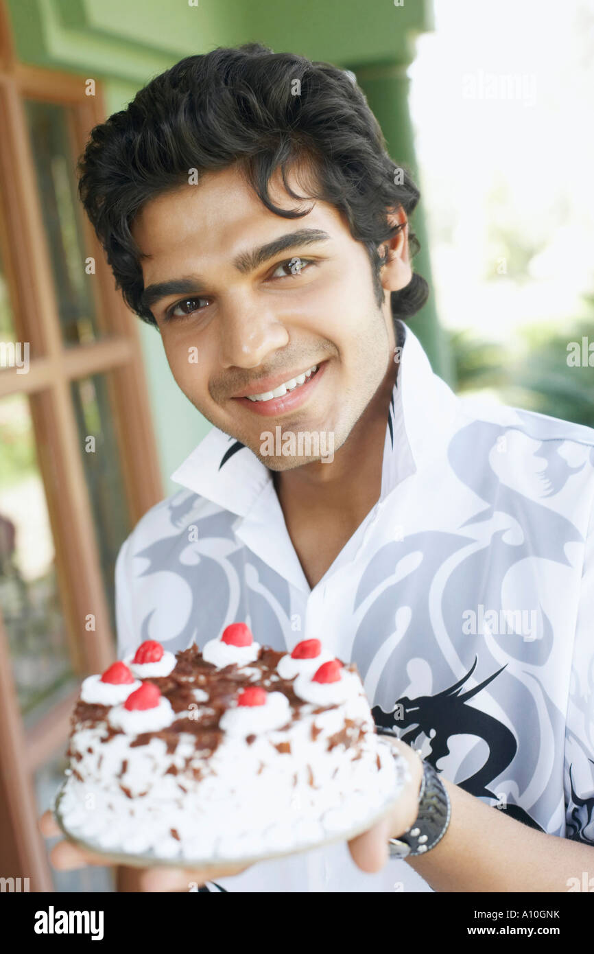 Portrait of a young man holding a birthday cake smiling Stock Photo - Alamy
