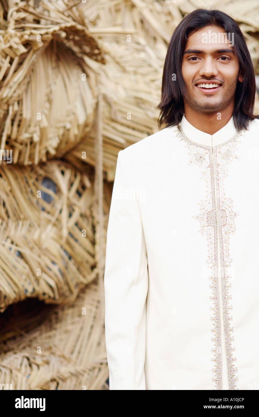 Portrait of a young man standing in front of a hut and smiling Stock ...