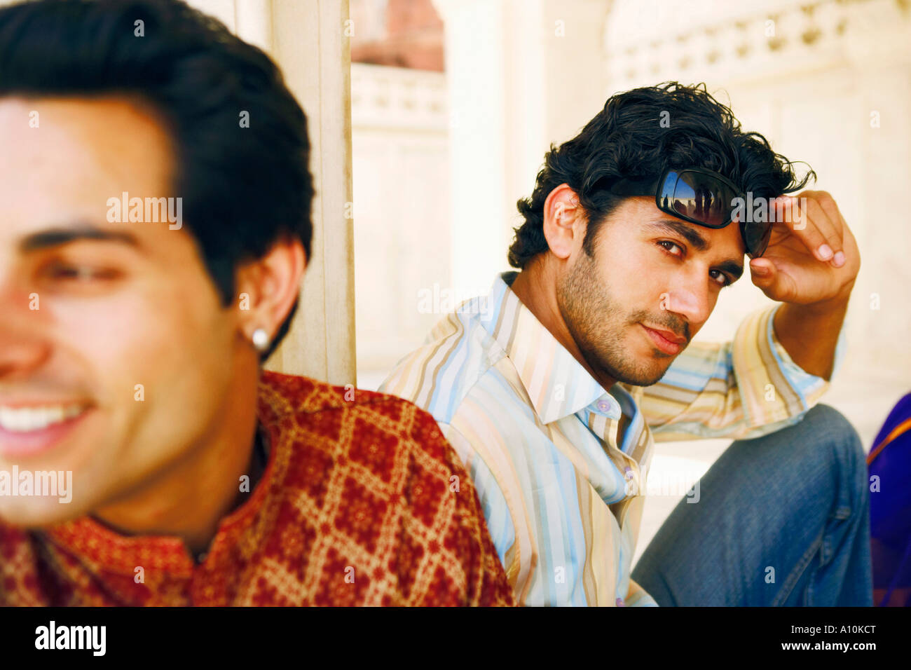 Portrait of a young man sitting with another young man behind him Stock ...
