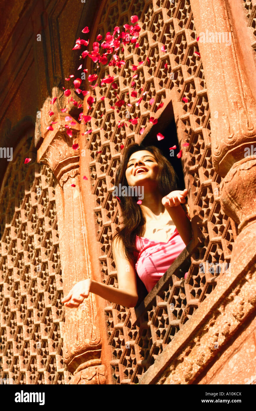 Low angle view of a young woman throwing rose petal from a window Stock ...