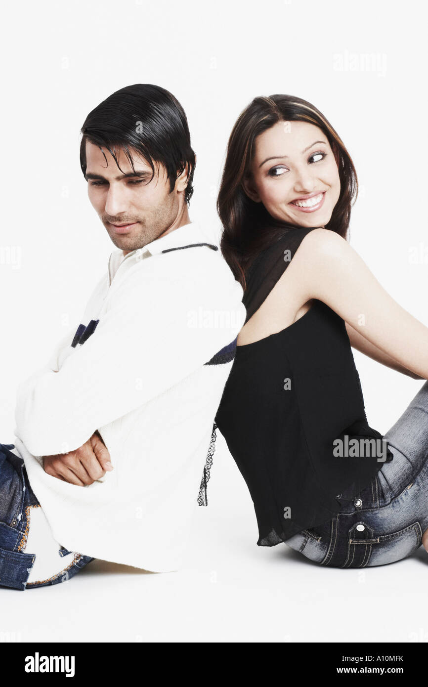 Side profile of a young couple sitting back to back Stock Photo - Alamy