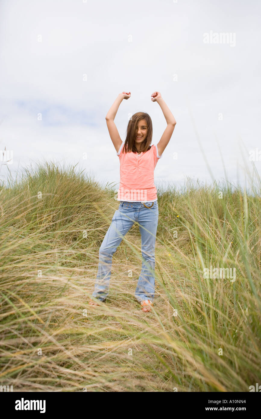 Teenage Girl Standing with Arms Raised above her Head on Coastal Dunes ...