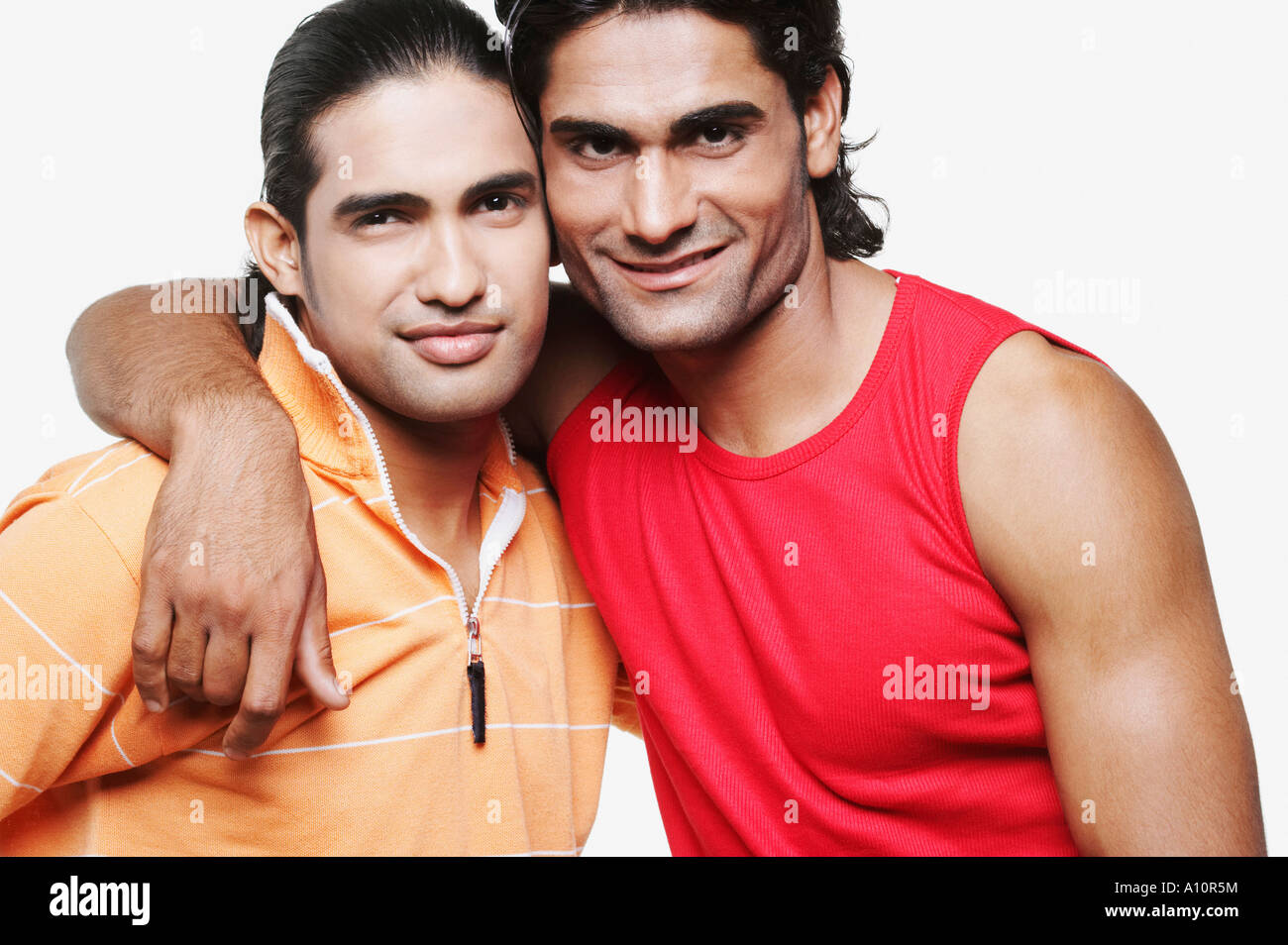 Portrait of two young men smiling with their arms around each other ...