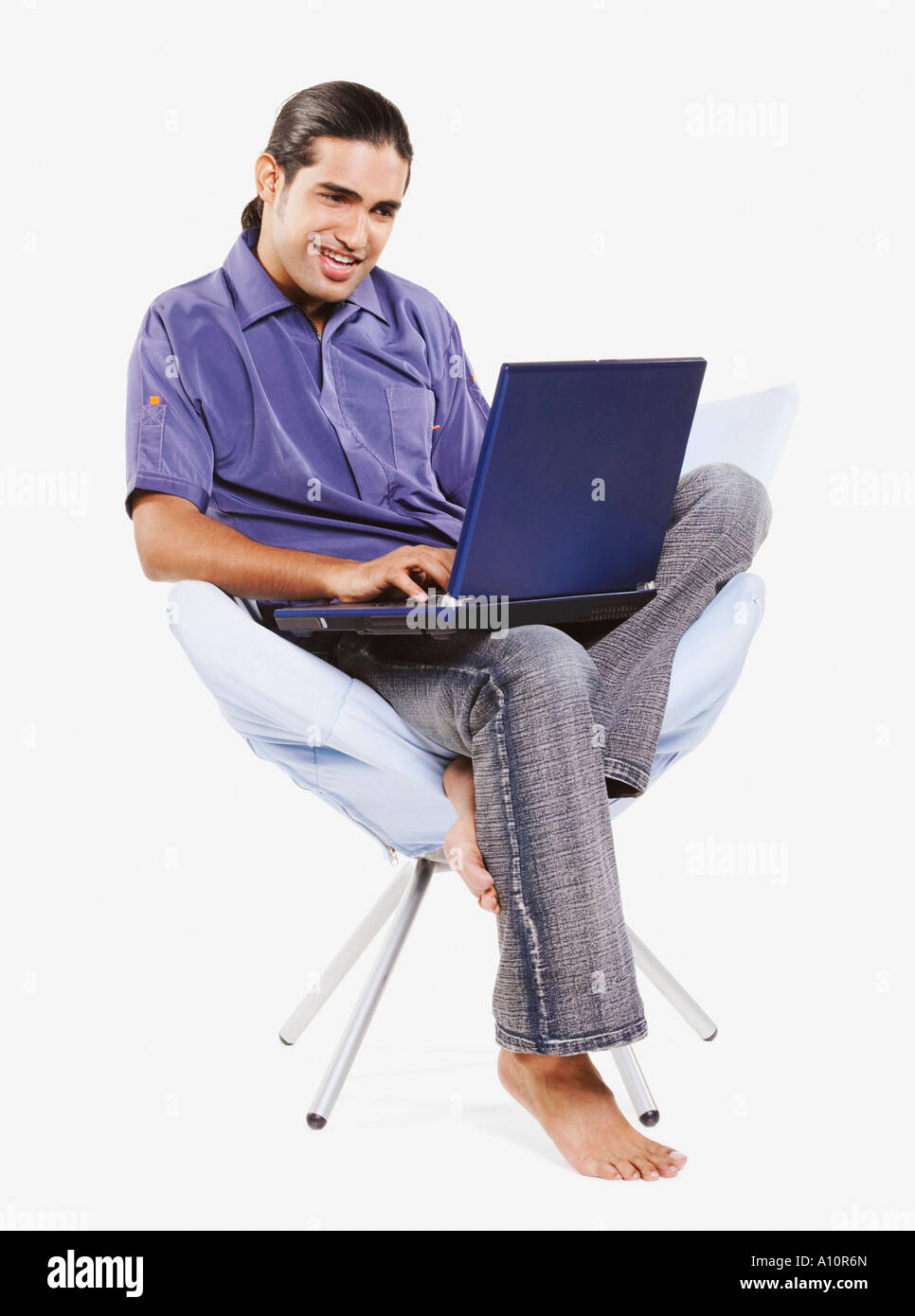 Young man sitting on a chair and using a laptop Stock Photo - Alamy