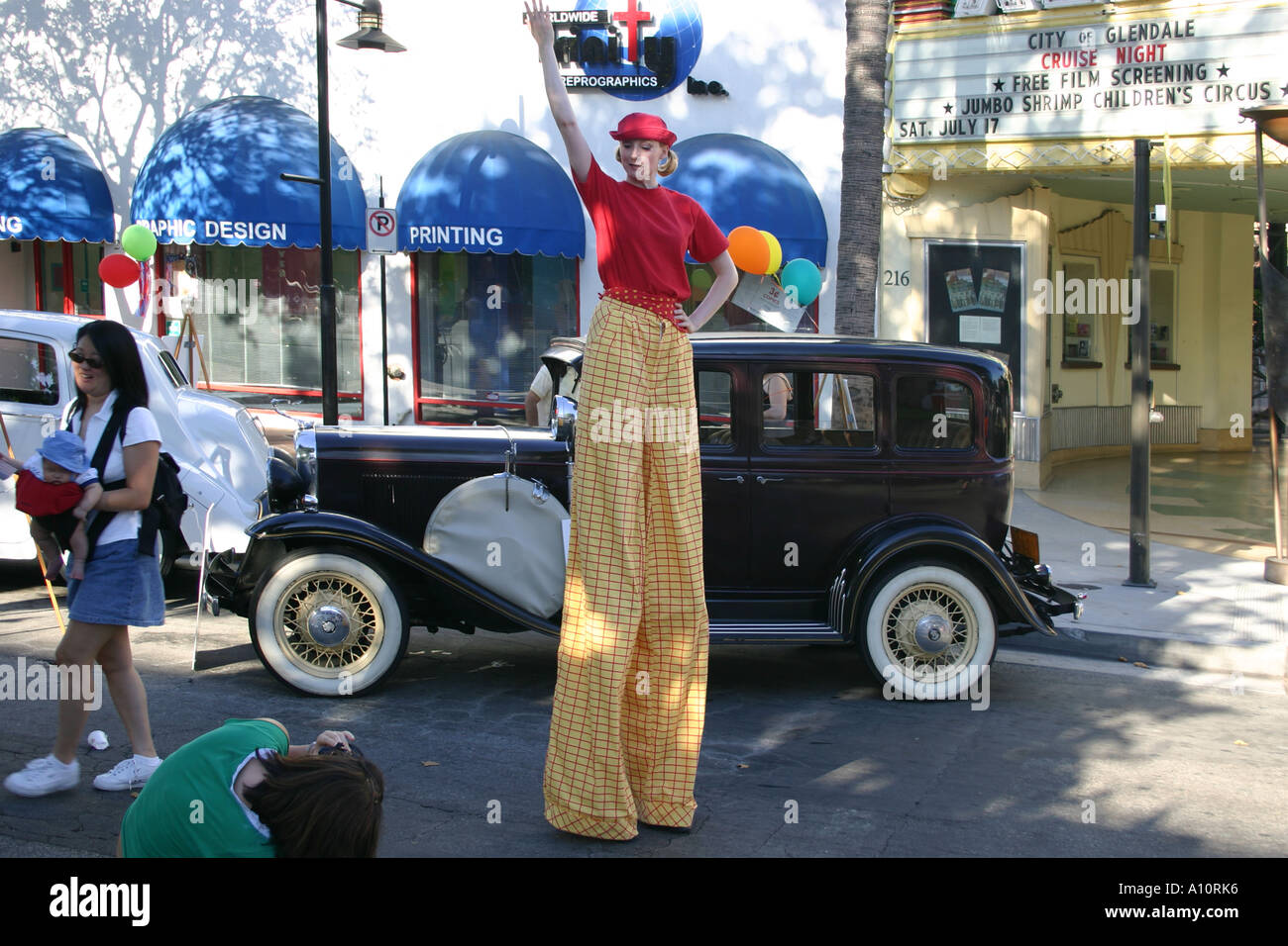 Street performer on stilts poses for photographer at classic car show ...