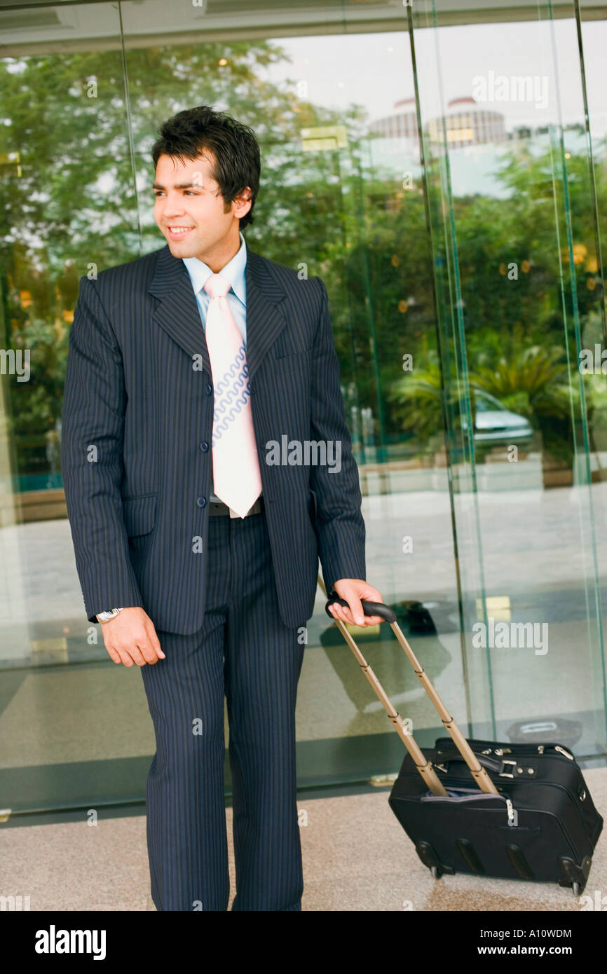 Businessman holding a suitcase and smiling Stock Photo - Alamy