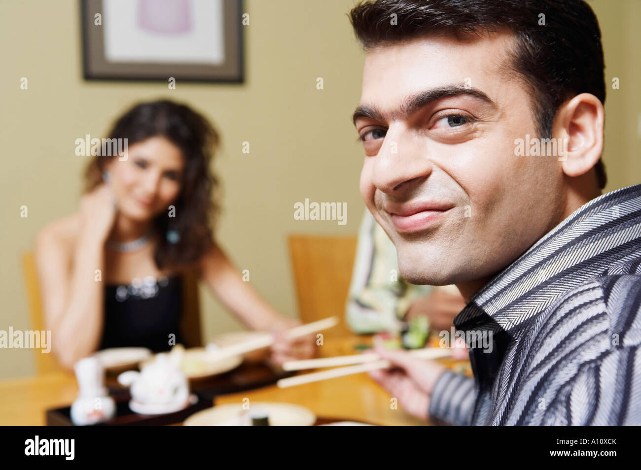 Portrait of a young man sitting at the dining table with his friends ...