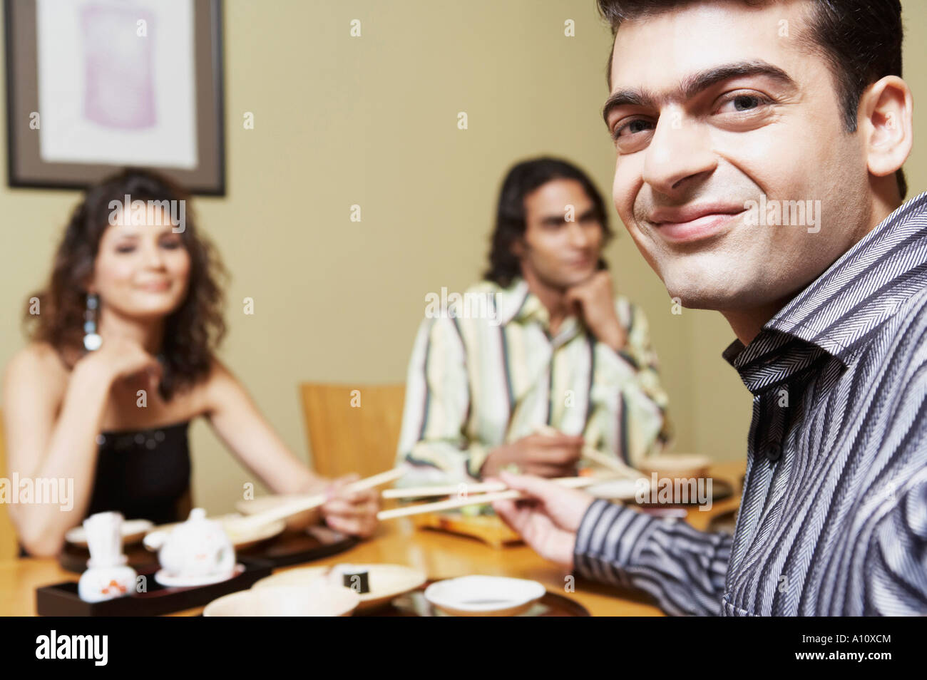 Portrait of a young man sitting at the dining table with his friends ...