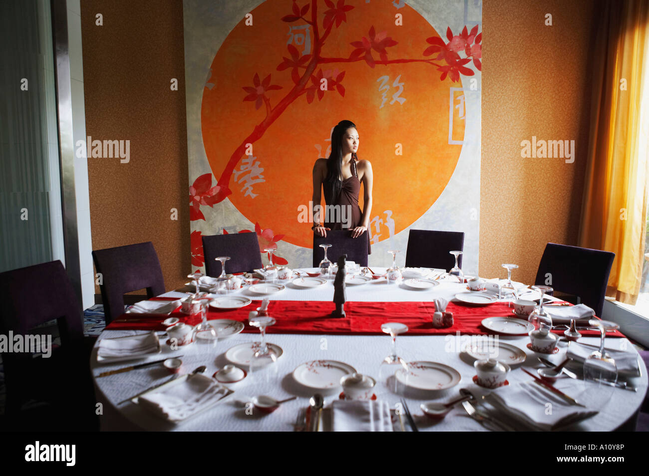 Young woman standing behind a table in a restaurant Stock Photo - Alamy