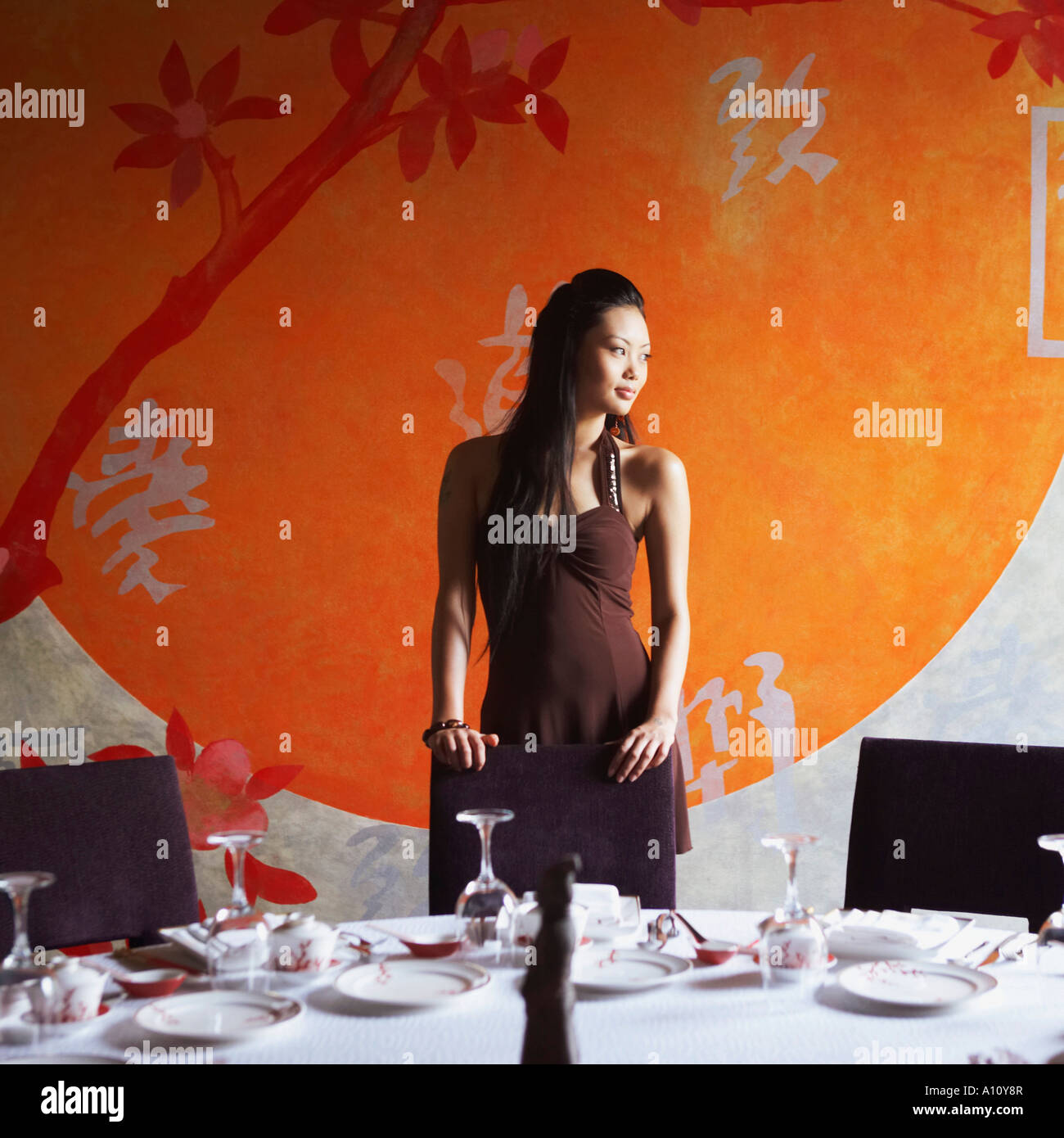 Young woman standing behind a table in a restaurant Stock Photo - Alamy