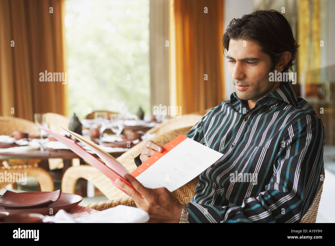 Young man sitting in a restaurant and reading a menu card Stock Photo ...