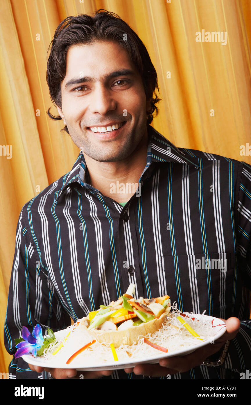 Portrait of a young man holding food in a plate Stock Photo - Alamy