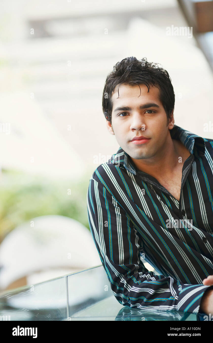 Portrait of a young man leaning against a glass Stock Photo - Alamy