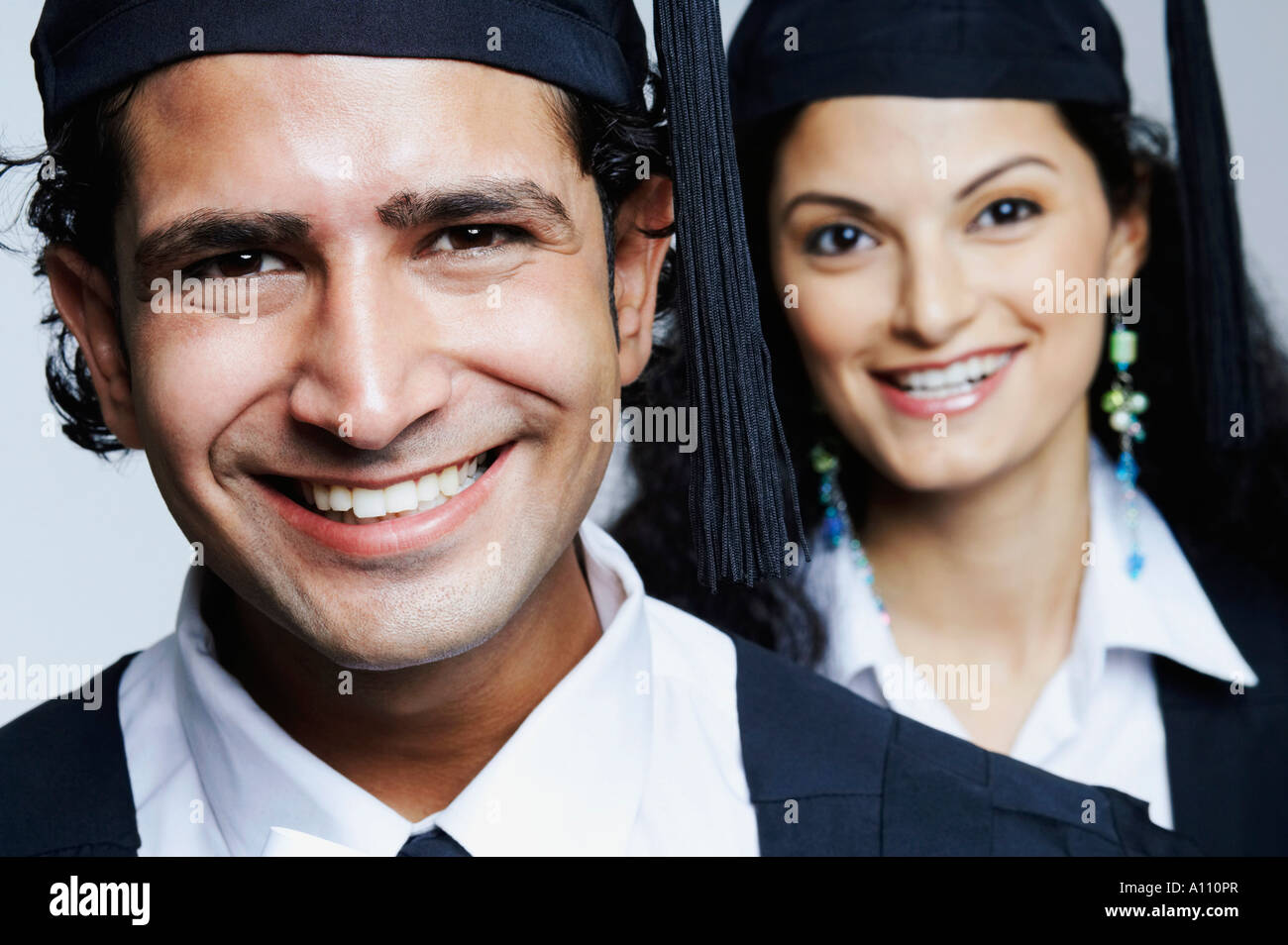 Portrait of a male graduate smiling with a female graduate behind him ...
