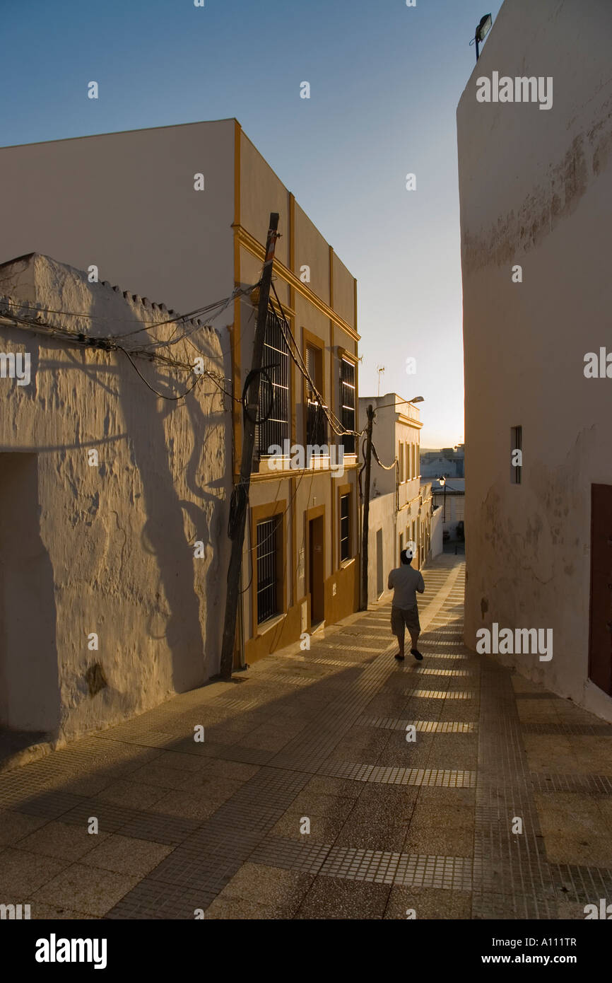 A man walking down a narrow alley in a traditional Spanish town in the ...