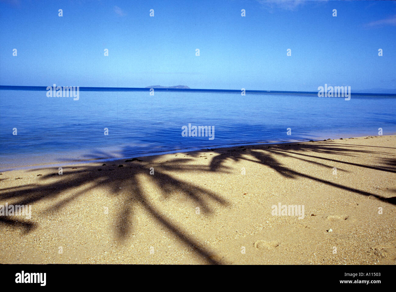 A SMOOTH SAND BEACH BLENDING INTO FLAT CALM WATER WITH AN ISLAND IN THE ...