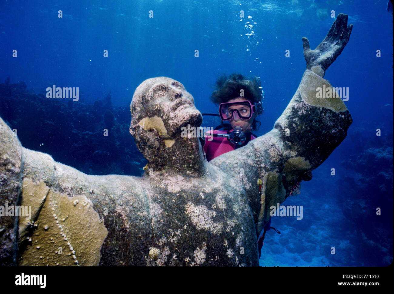A FEMALE SCUBA DIVER LOOKS AT THE UNDERWATER STATUE OF CHRIST OF THE ...