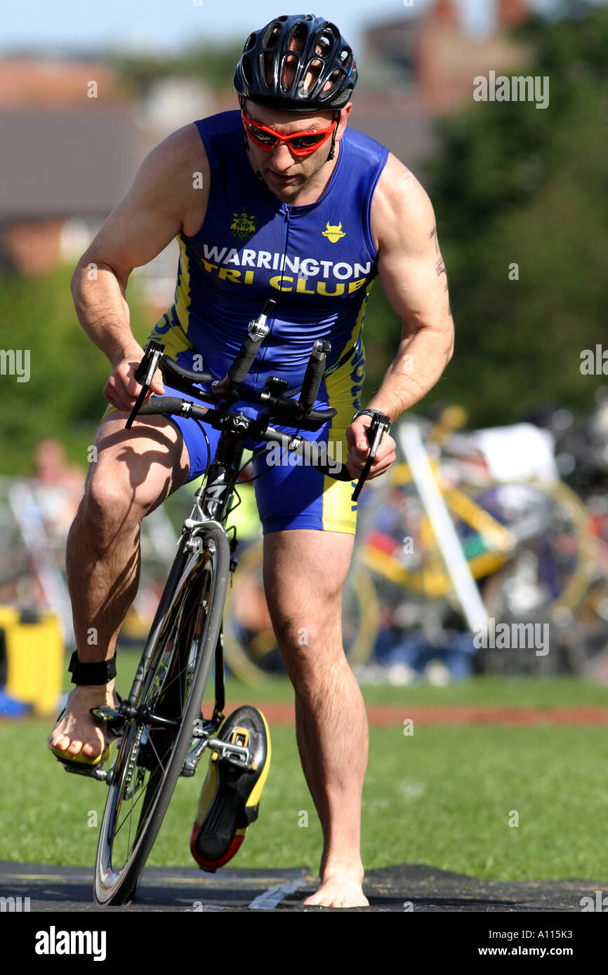 male triathlete climbs onto bike at transition area Stock Photo - Alamy