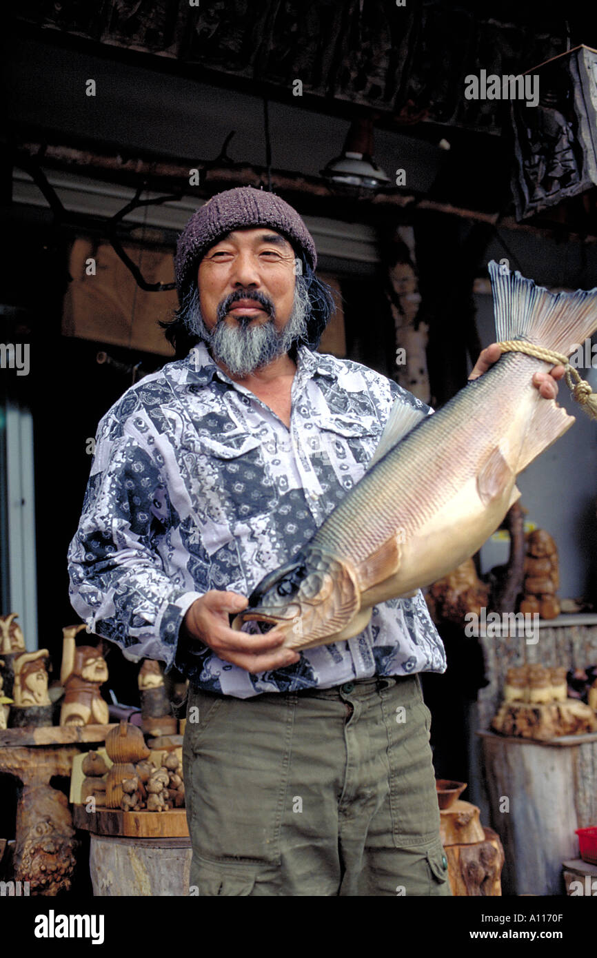Old Ainu man showing off his hand carved fish in the Kawayu village ...