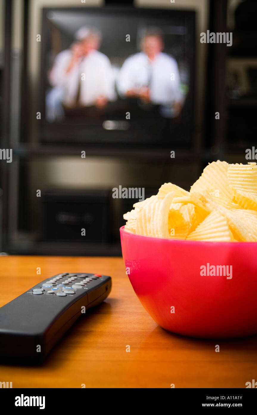 Remote control and potato chips in front of TV Stock Photo - Alamy