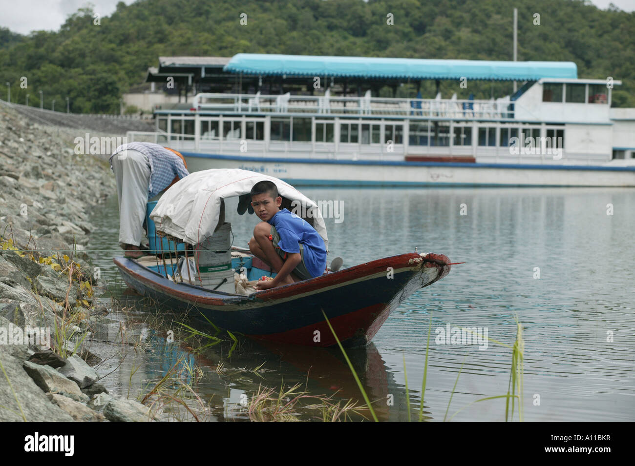 Boy and man in a fishing boat on Sirikit Reservoir Stock Photo - Alamy