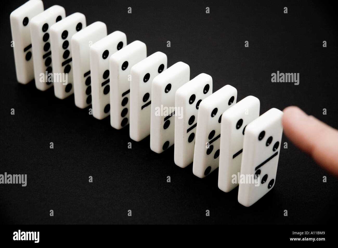 Dominos in a row on a black background being pushed over Stock Photo ...