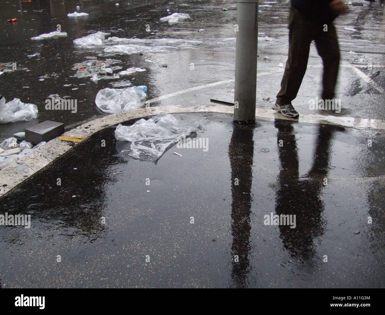 one man walking and litter on rain soaked street in town Stock Photo ...