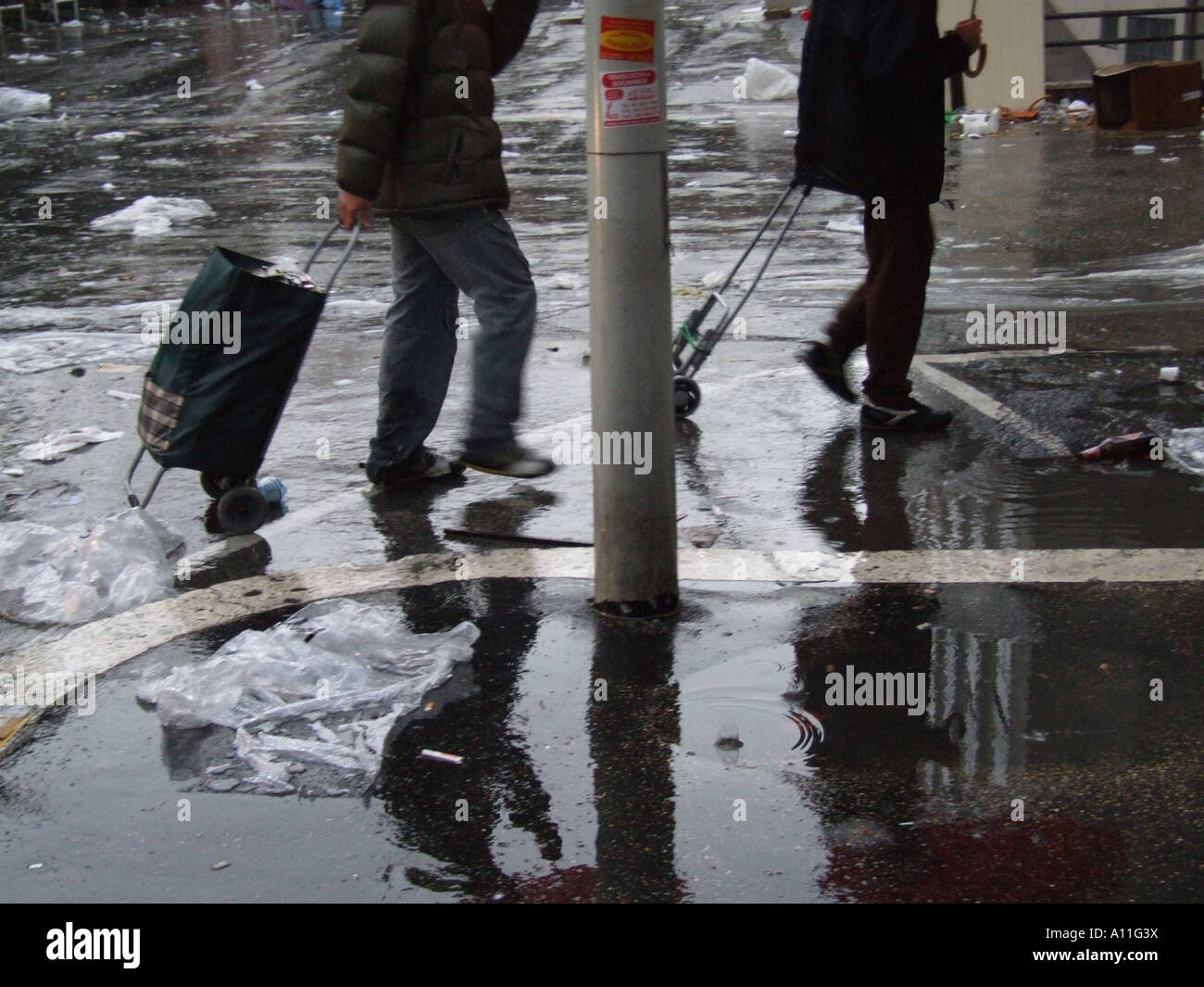 two men walking and litter on rain soaked street in town Stock Photo ...