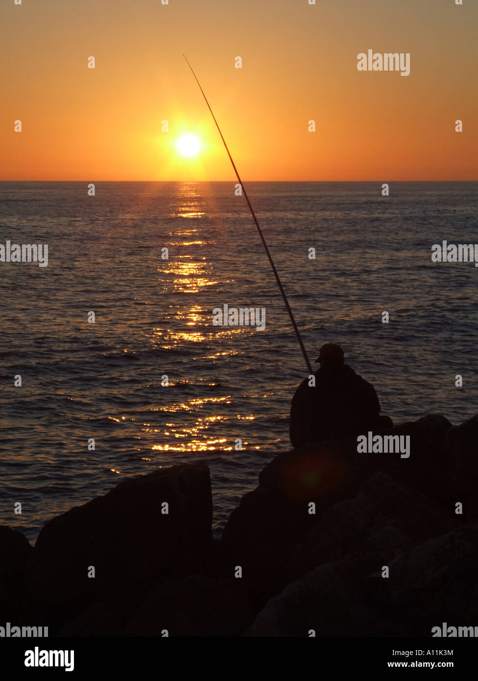 man fishing in sea with beautiful red sunset Stock Photo - Alamy