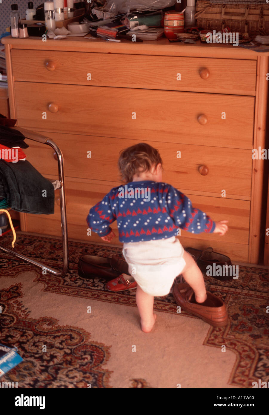 Little girl toddler in a droopy nappy diaper trying on an adult shoe ...