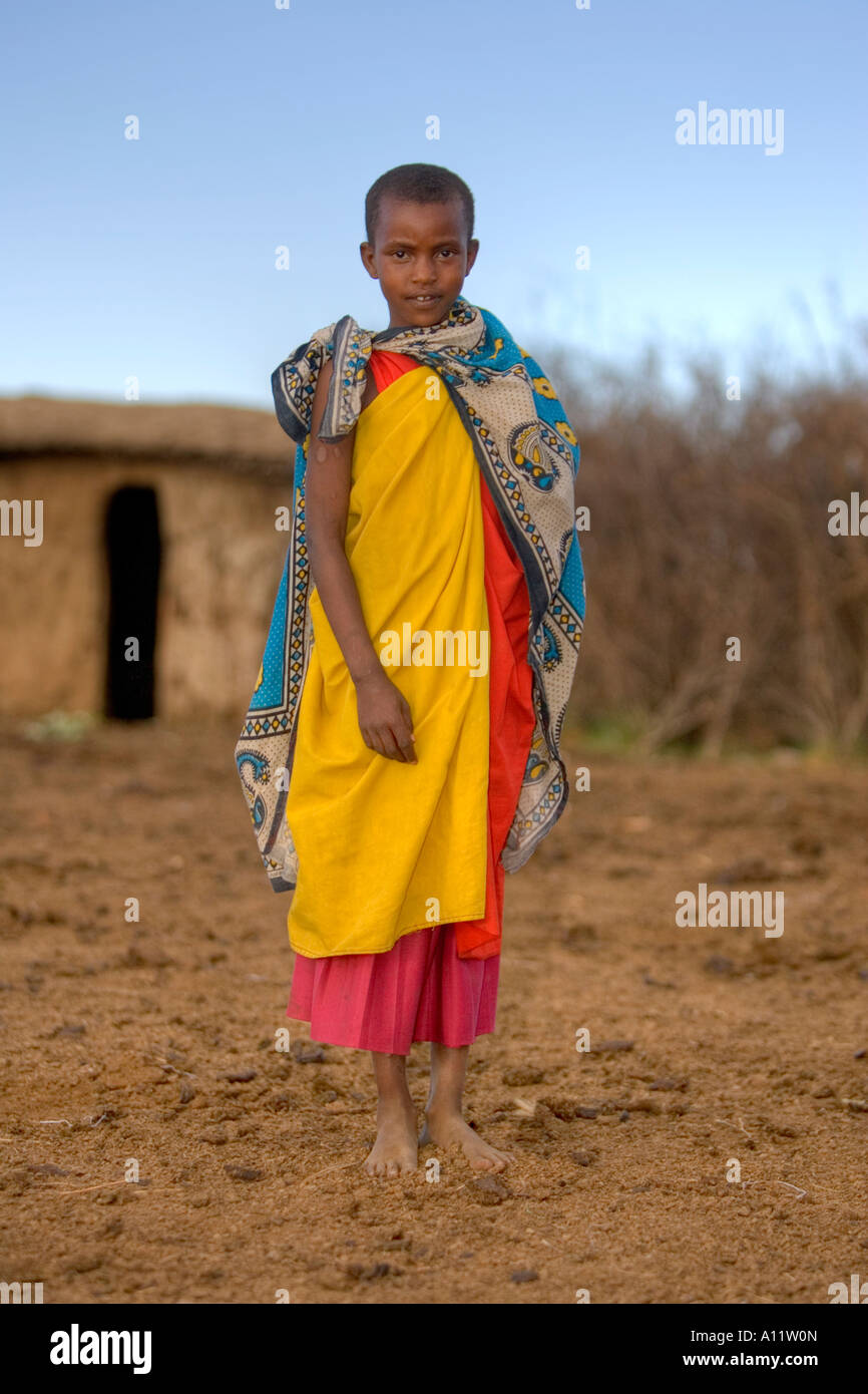 Masaai boy in traditional dress posing in front of a hut in his village ...