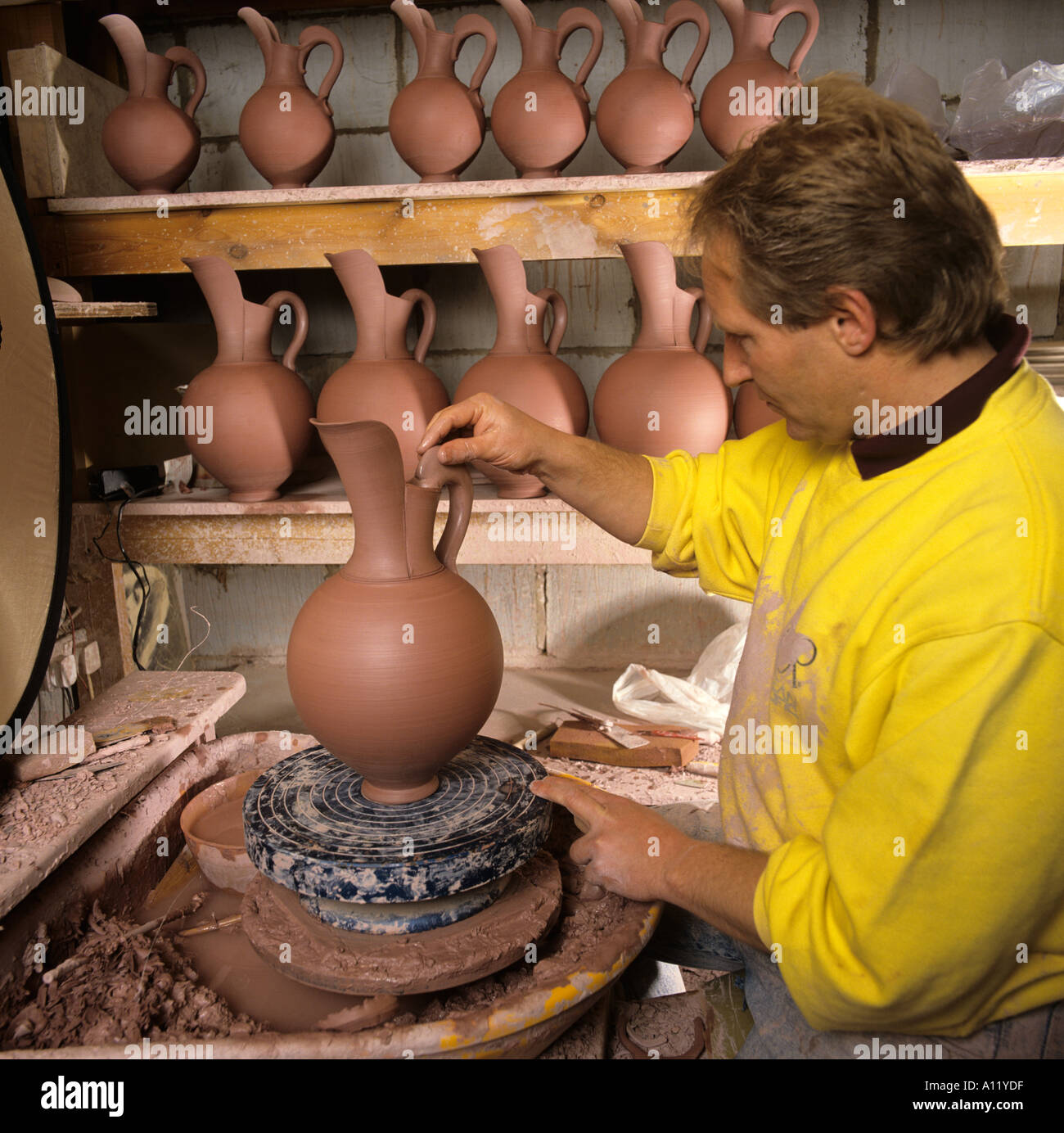 A potter working on a jug before firing in a workshop near Stroud in ...